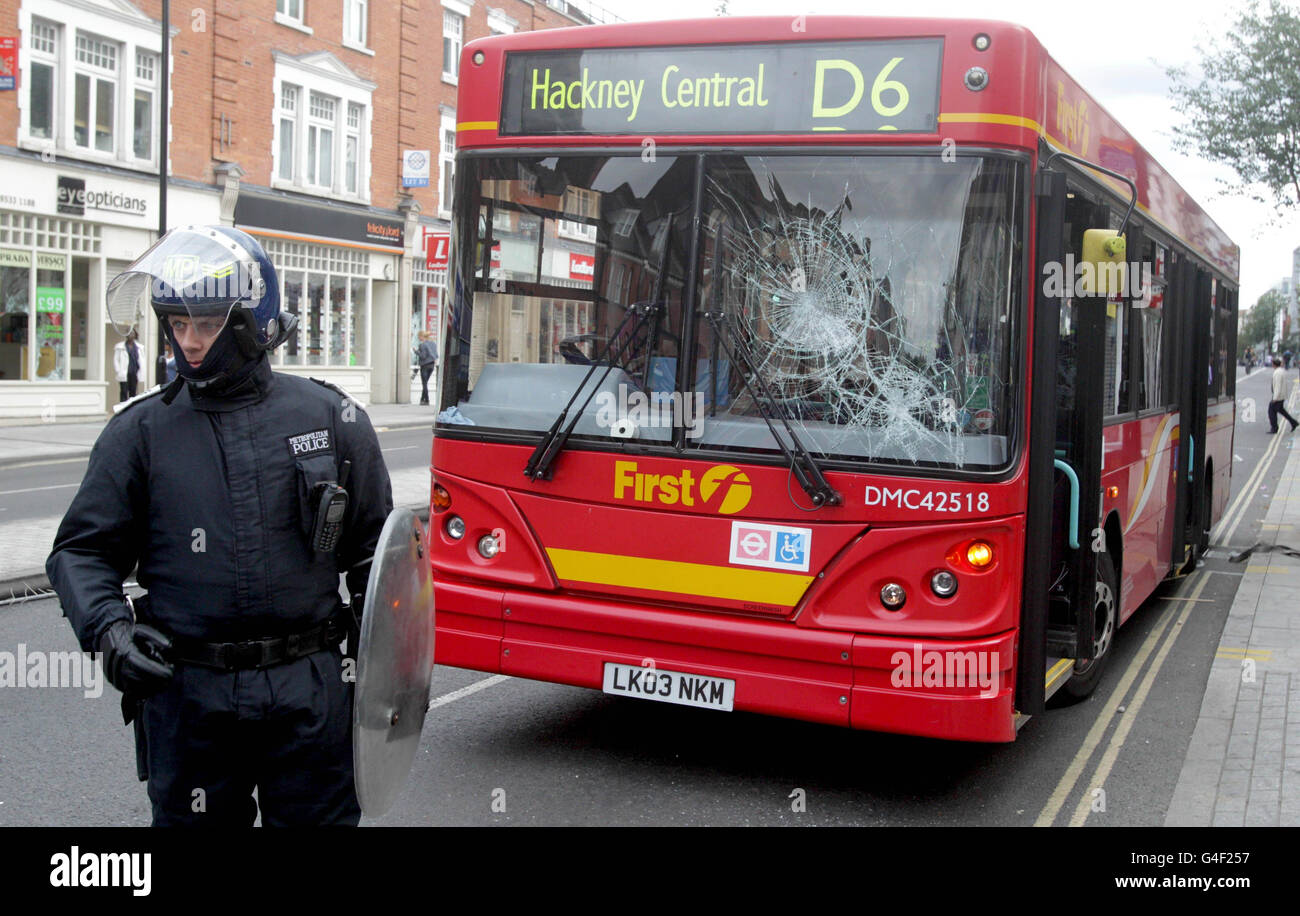 A police officer stands near a bus with a smashed window in Hackney ...