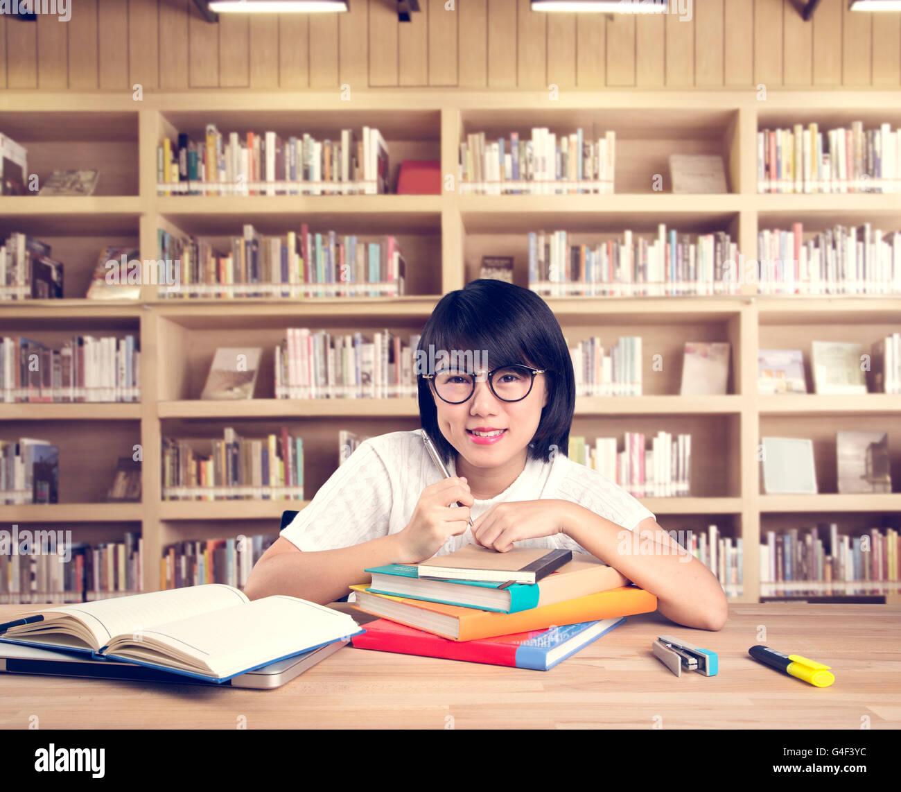 Portrait of clever asian student with open book reading it in library ...