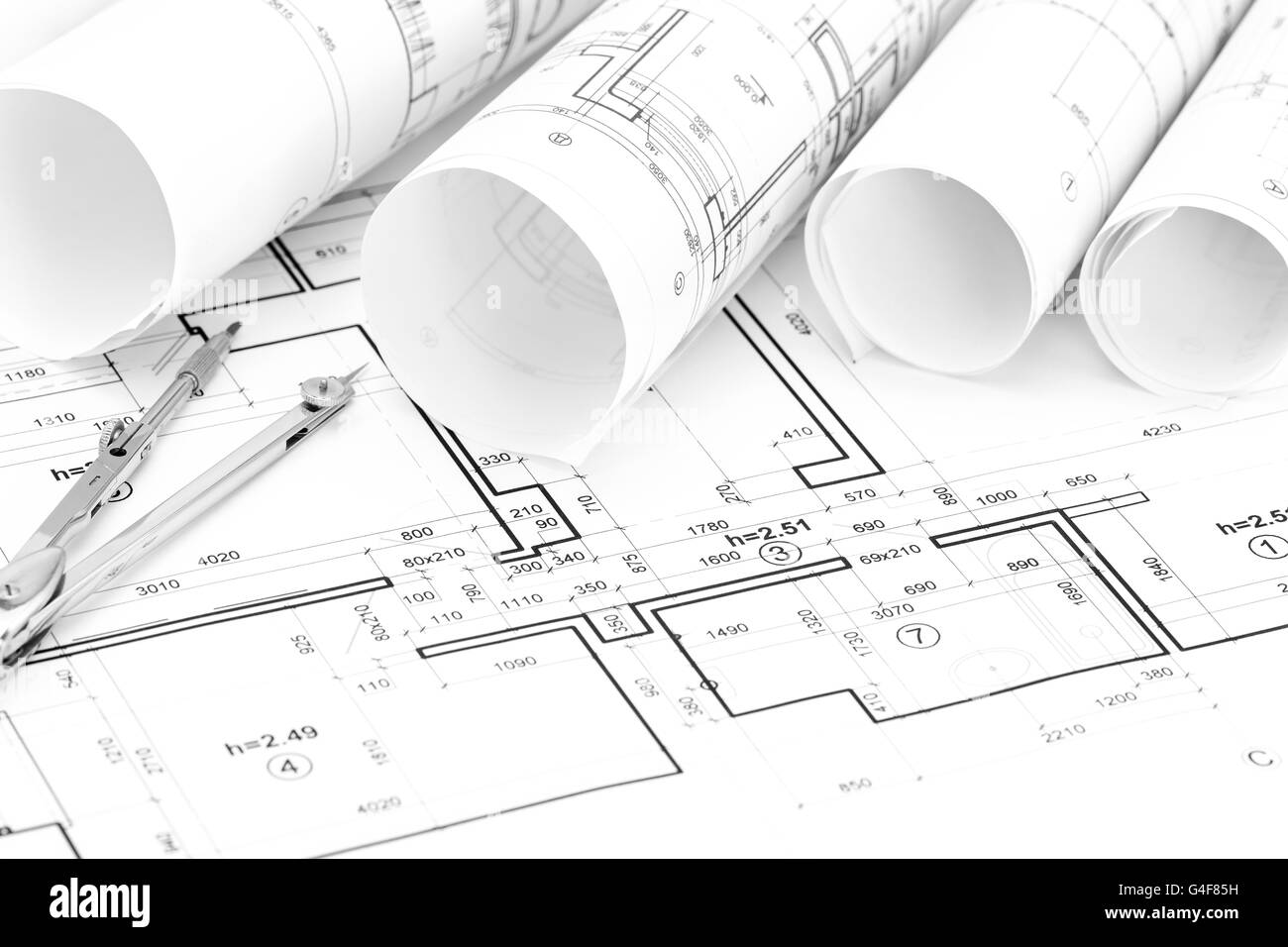 rolls of architectural blueprints and house plan with drawing compass ...