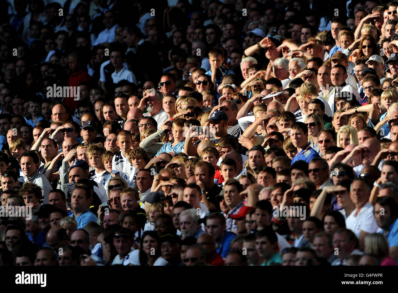 Fans shield their eyes from the sun as they watch the action from the ...