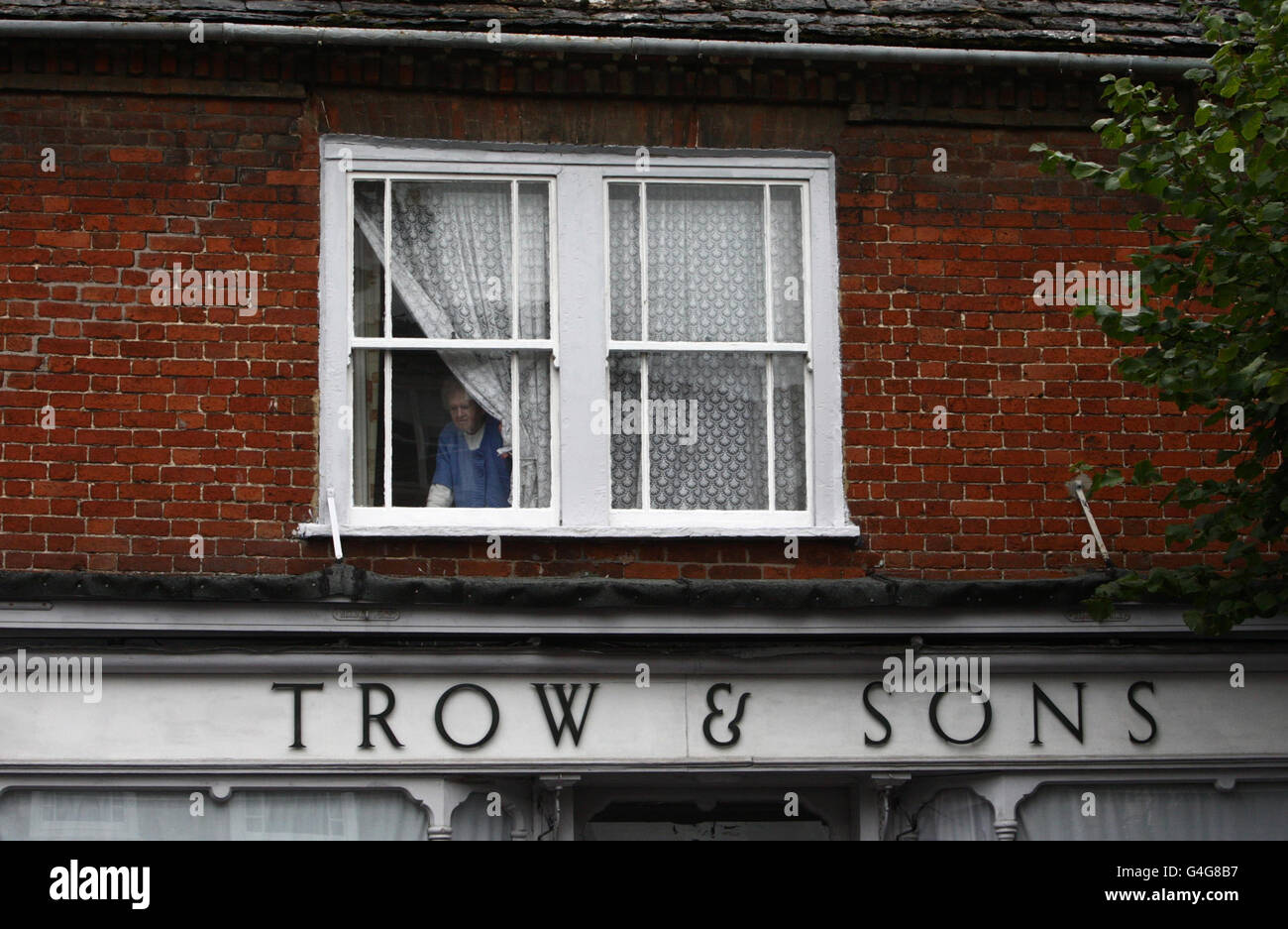 A local resident watches from a window as the hearse carrying the ...