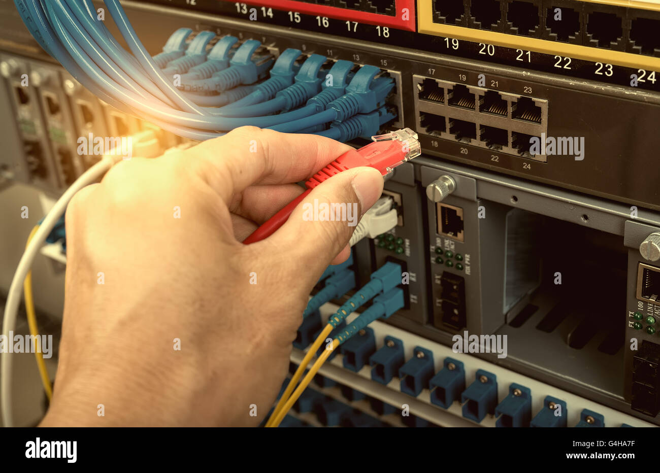 man working in network server room with fiber optic hub for digital ...