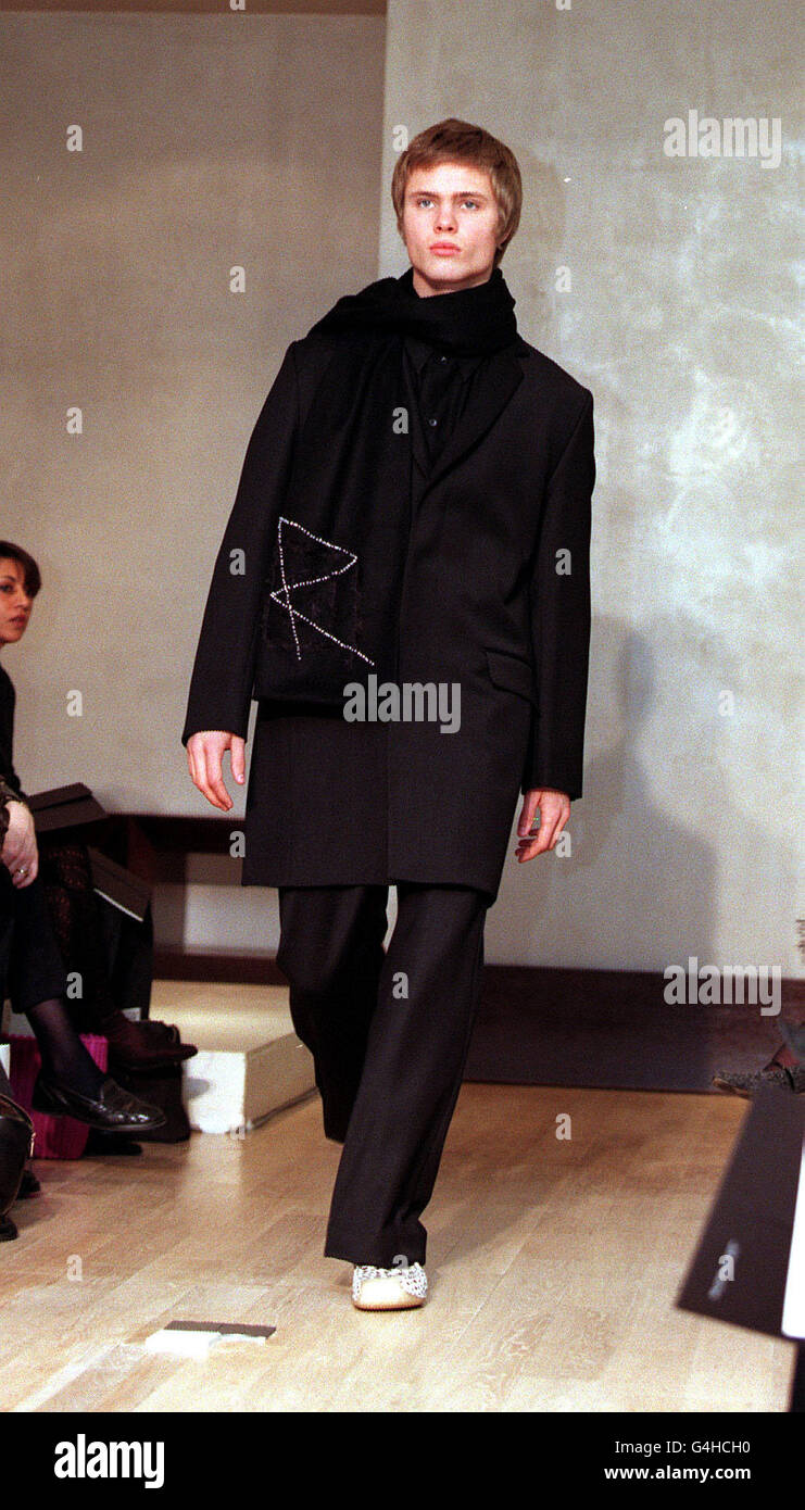A model presents a charcoal jacket and trouser with black scarf ...