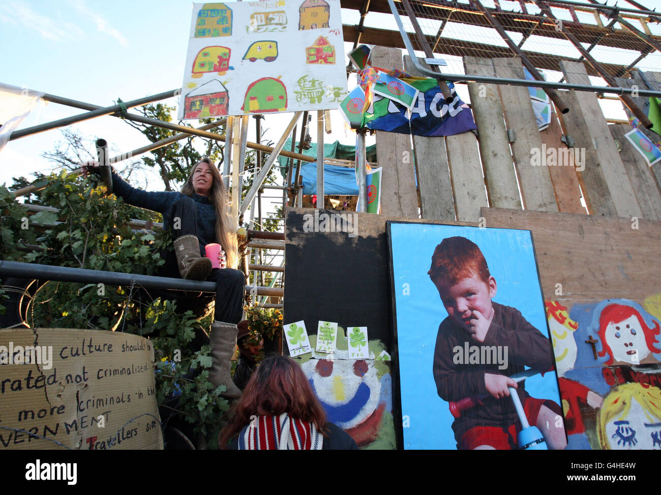 A woman looks out from the front gate at Dale Farm travellers' site at ...