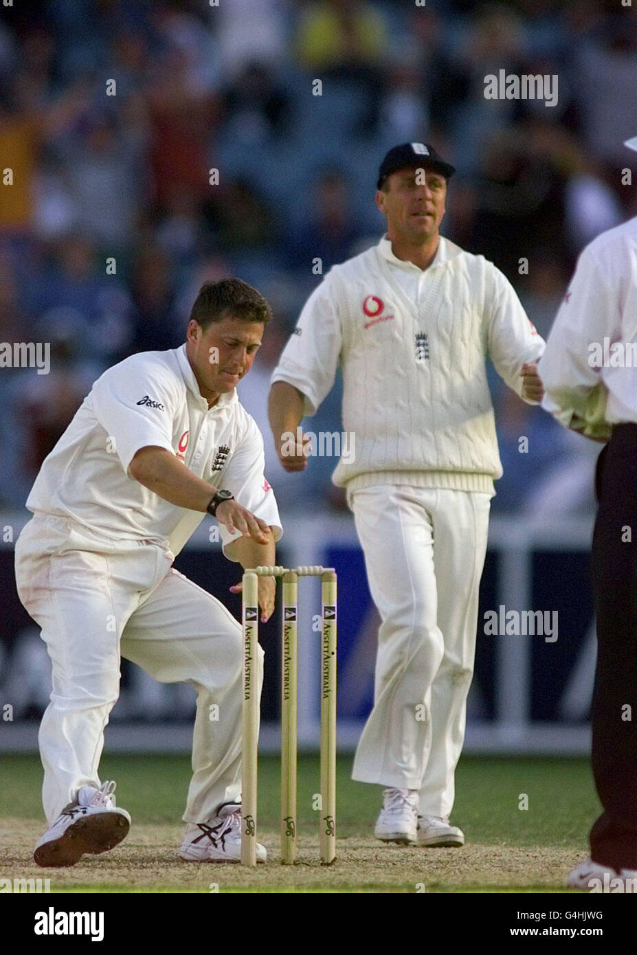 Darren Gough stoops to take a stump as captain Alec Stewart walks to thank one of the umpires ...