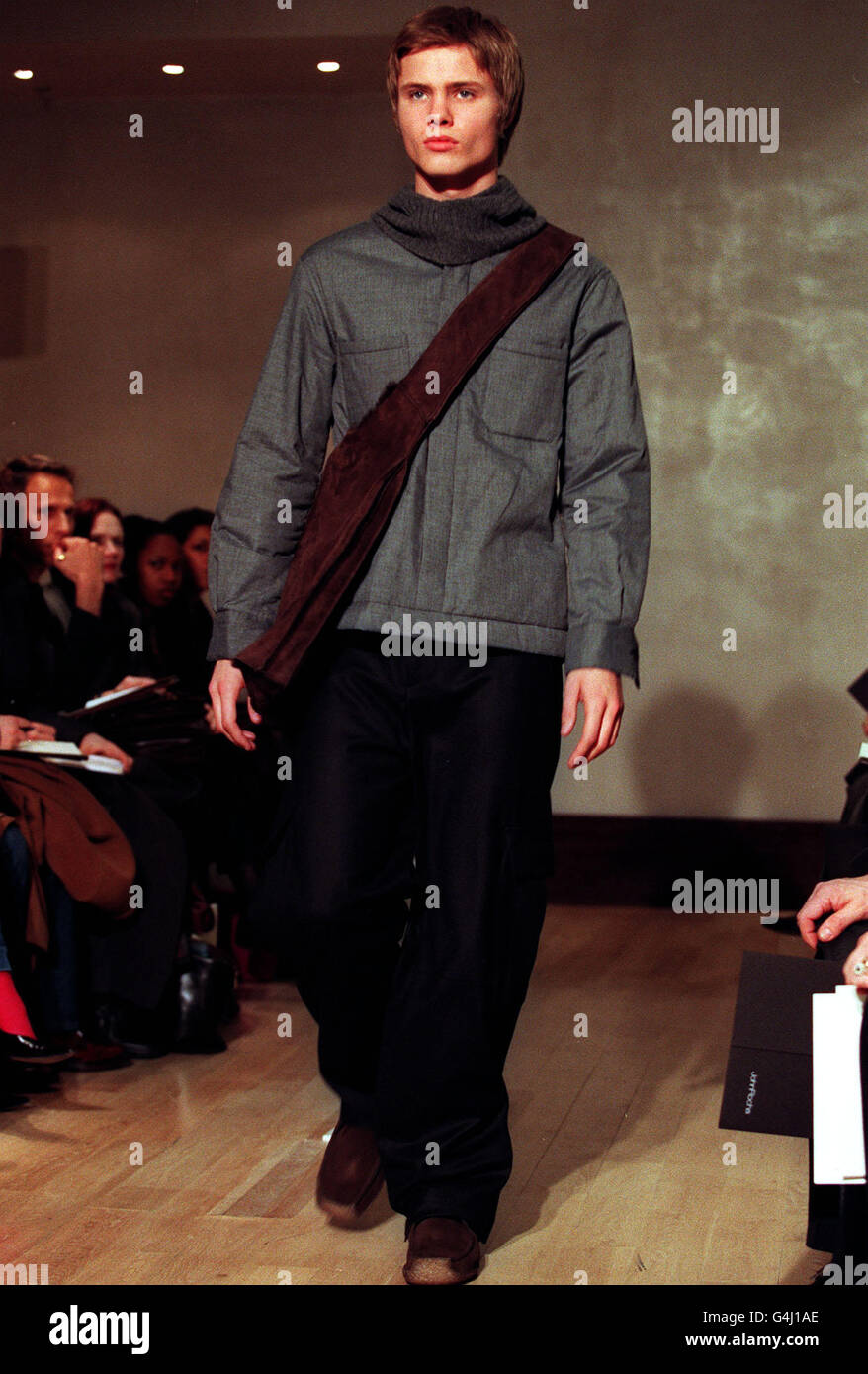 A model presents a grey jacket and charcoal trousers with brown suede ...