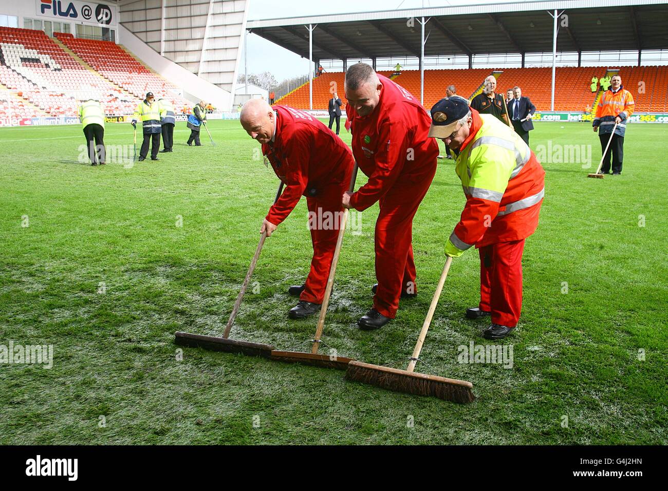 Ground staff attempt to sweep standing water from the playing surface ...