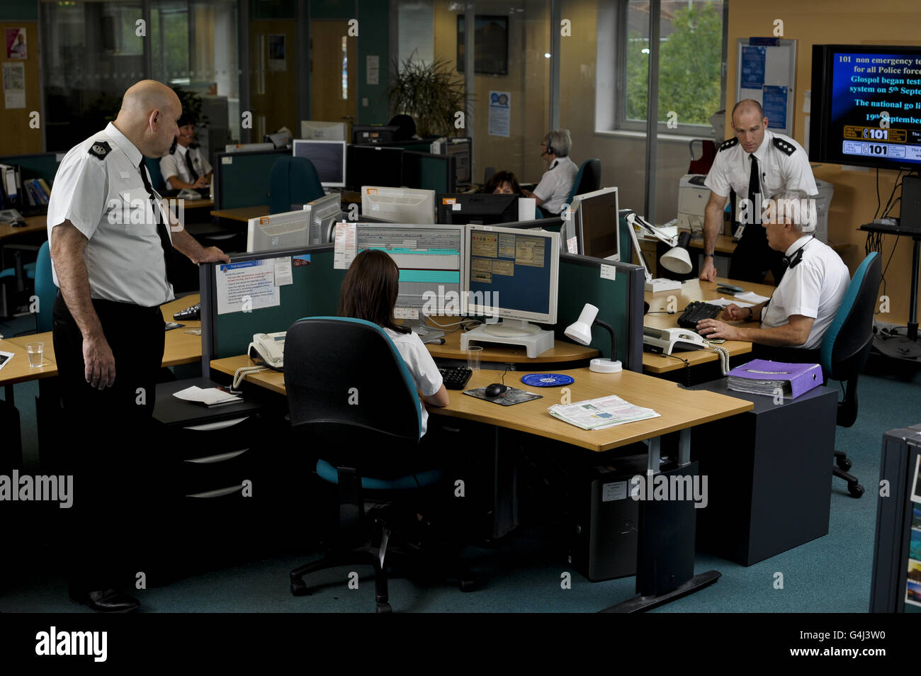 Police officers supervise staff as they take non-emergency calls from ...