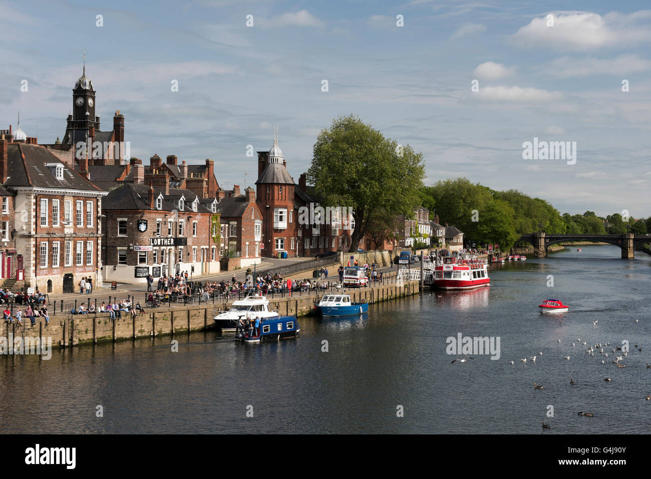 Lots of people drinking & relaxing in sun at busy riverside pub as ...