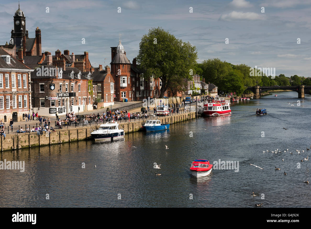 Lots of people drinking & relaxing in sun at busy riverside pub as ...