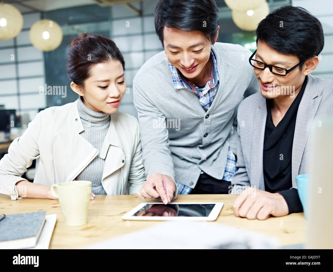a team of young asian entrepreneurs working in office using tablet ...