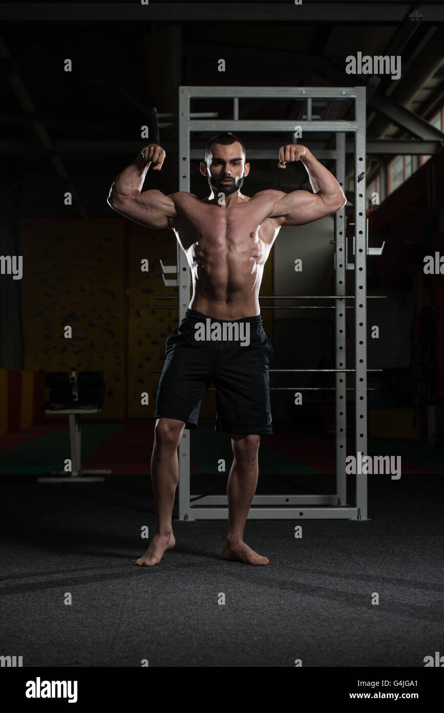 Young Man Standing Strong In The Gym And Flexing Front Double Biceps ...