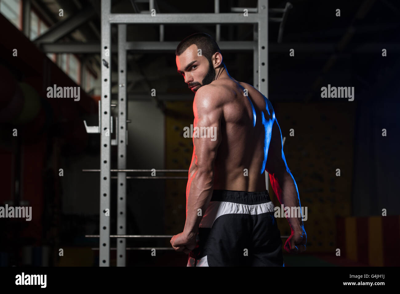 Young Man Standing Strong In The Gym And Flexing Side Triceps Pose ...