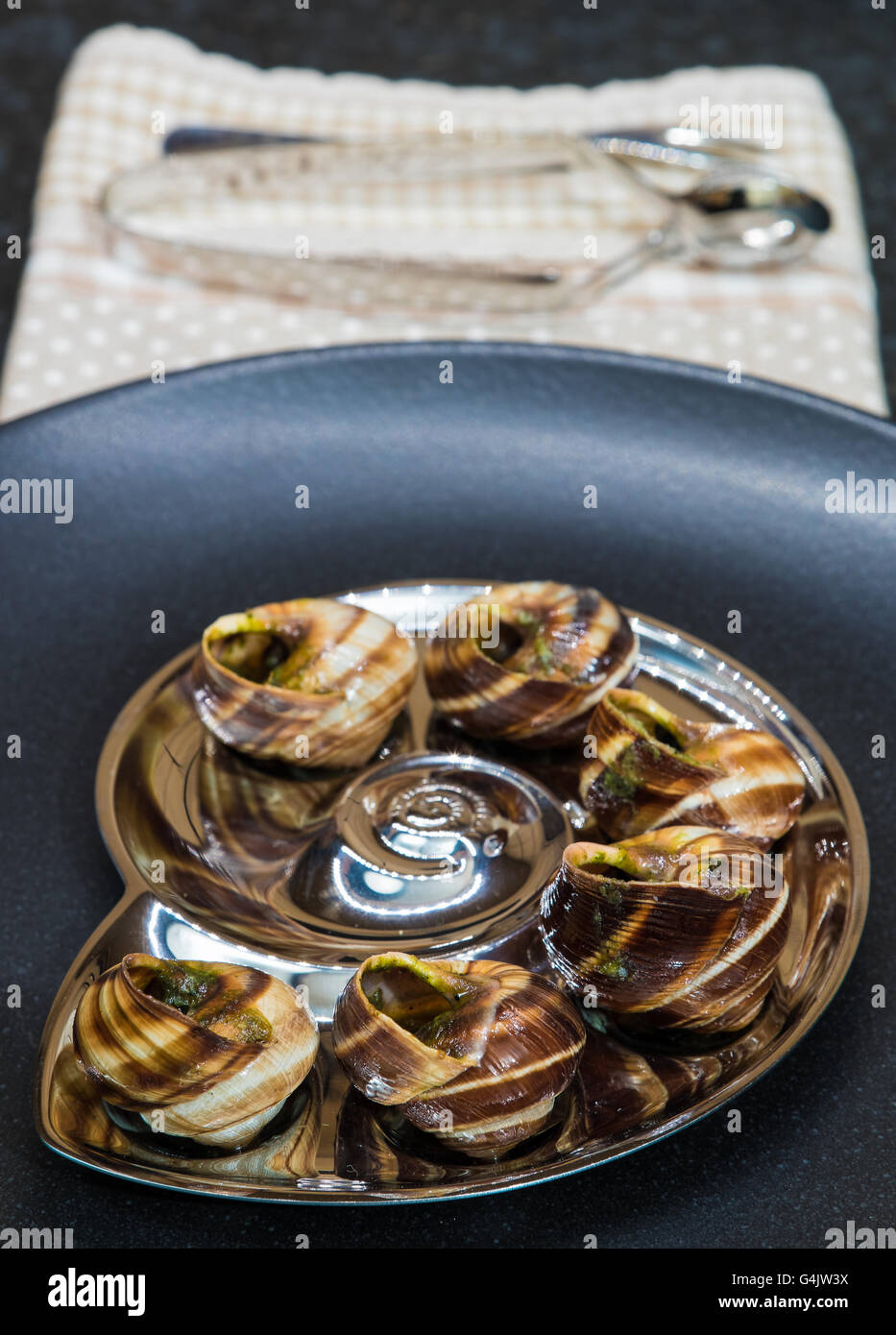 Prepared snails with garlic and parsley in black plate Stock Photo - Alamy