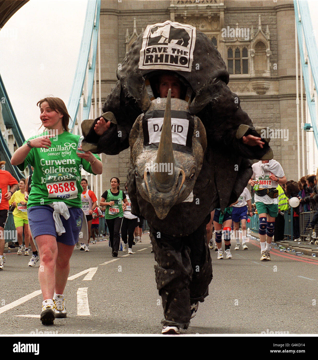 A fun runner dressed in a rhino costume passes under Tower Bridge ...