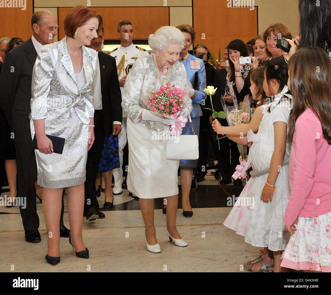 Queen Elizabeth II is given flowers by a small girl as Australian Prime ...
