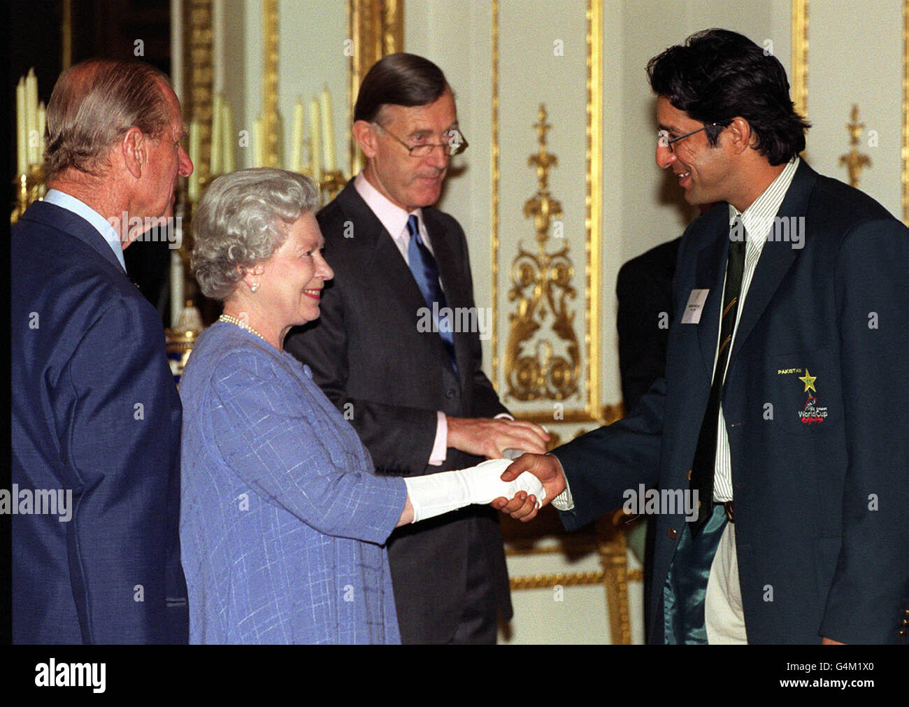 The Queen shakes hands with Pakistani cricketer Wasim Akram, watched by ...