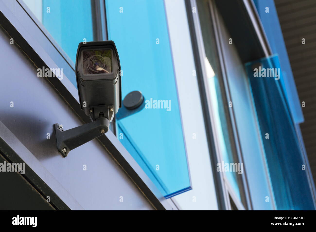 Grey security camera attached to wall blue windows background Stock ...