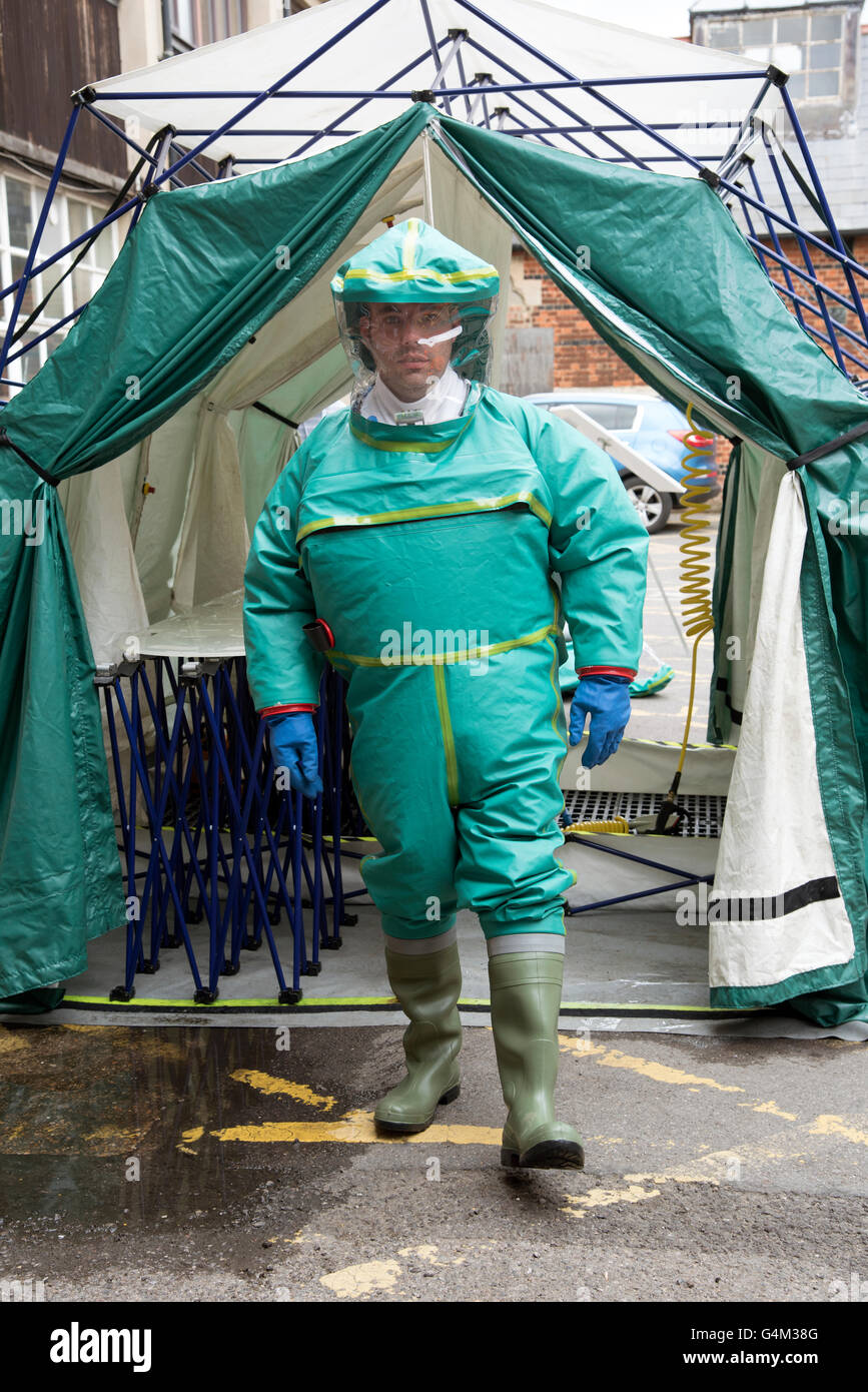 Man wearing a decontamination suit walking from a decontamination tent ...