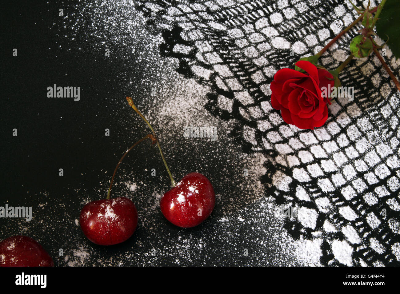 Sweet cherry against black background, lacy drawing from icing sugar ...