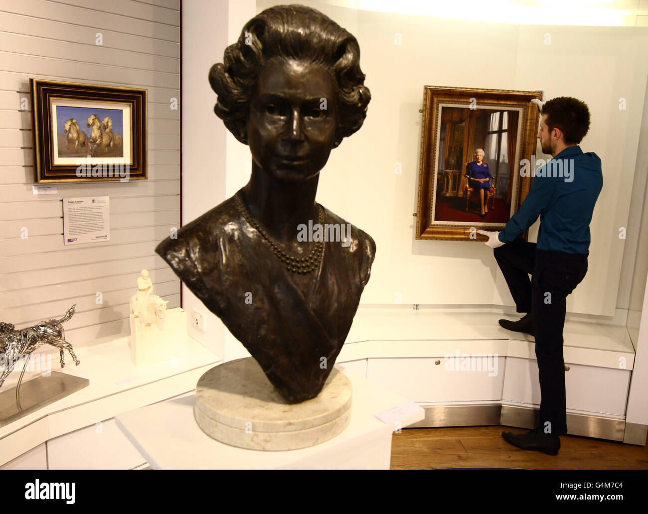 Gallery Manager Alex Prior hangs a portrait of HM Queen Elizabeth II ...