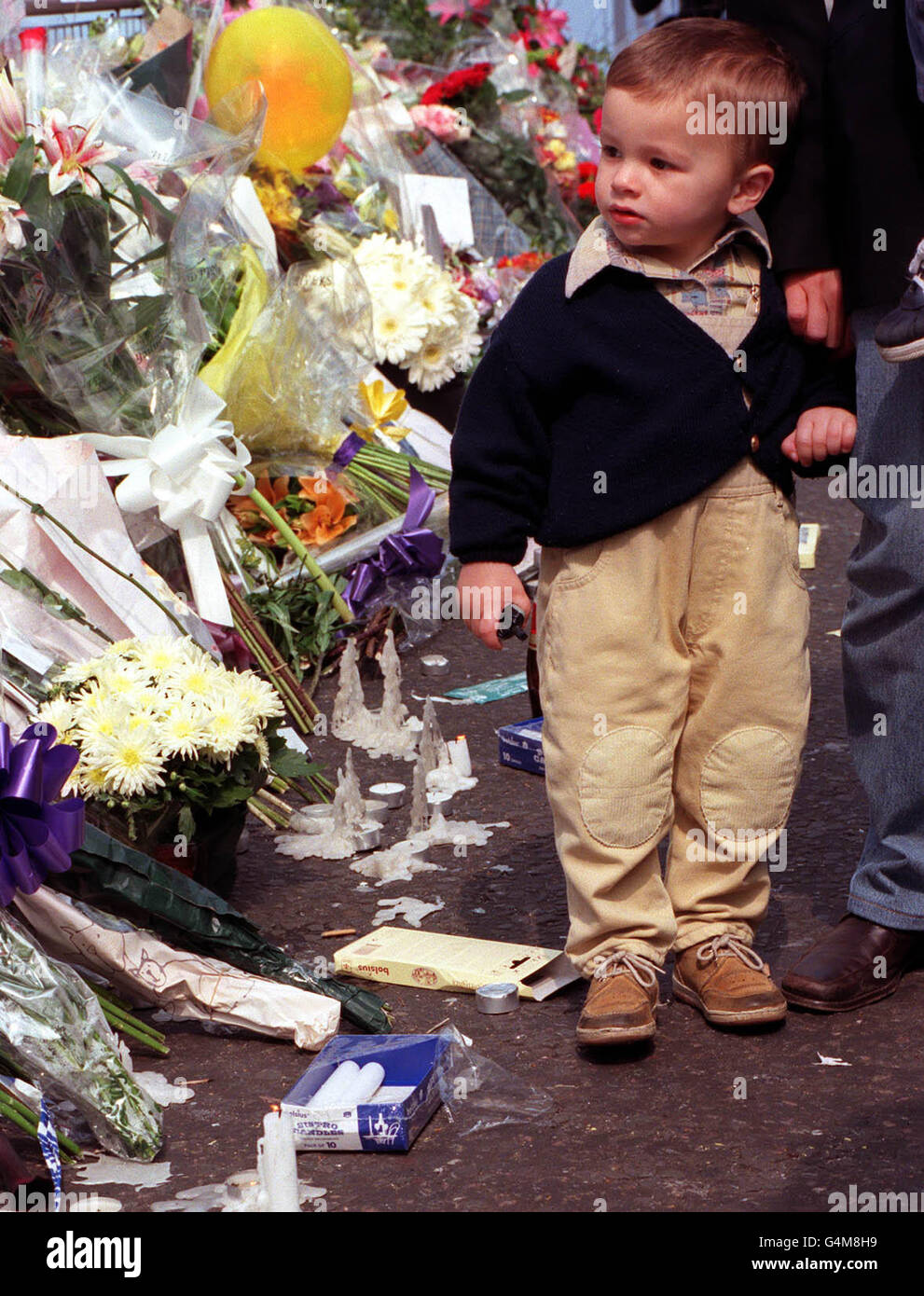 A young child gazes over dozens of bouquets which mark the spot where ...