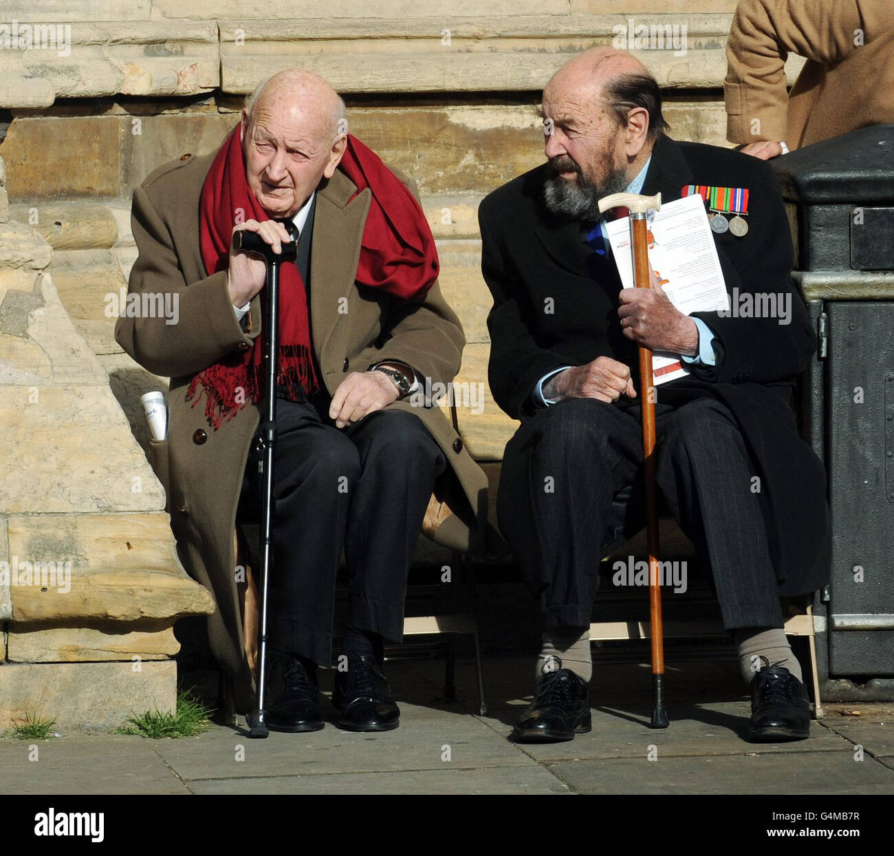 WWII veterans (names not given) sit in the sun following a memorial ...