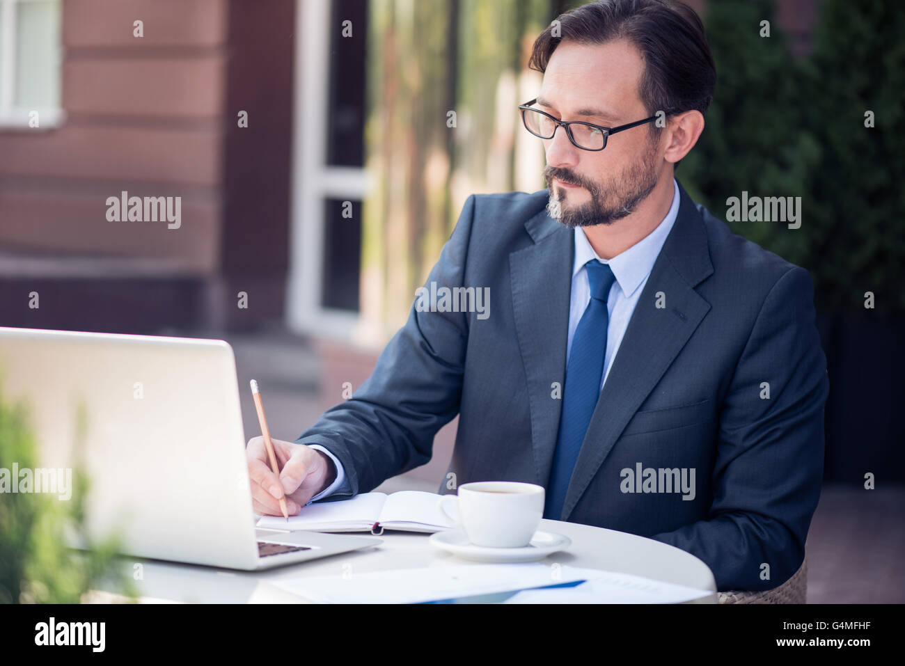 Handsome serious man sitting at the table Stock Photo - Alamy