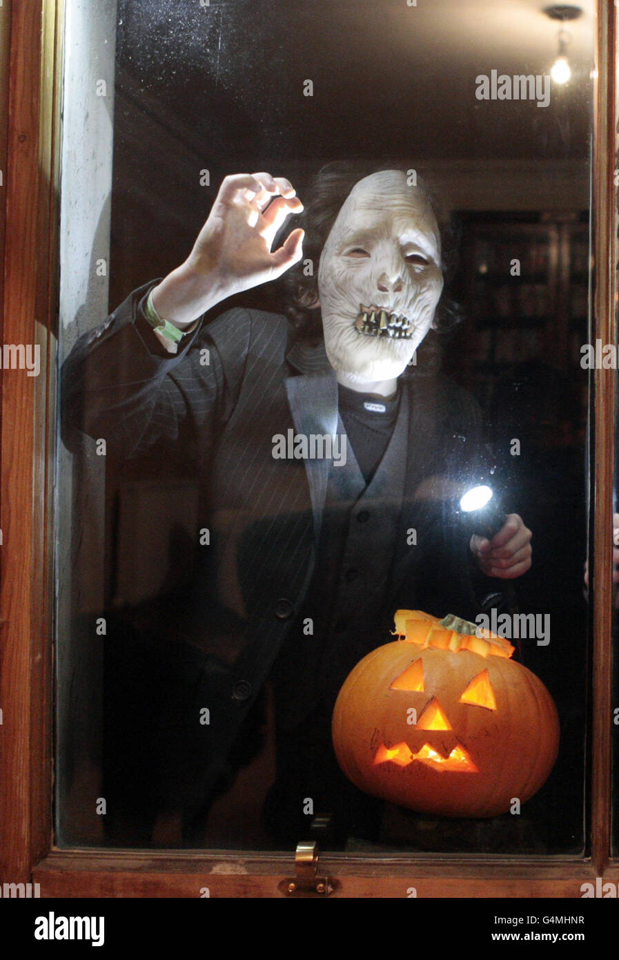 A child in a Halloween costume knock on windows during Halloween night ...