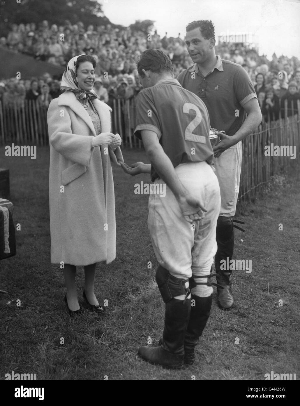 Queen Elizabeth II presents a medal to J.L Lucas, a member of the ...