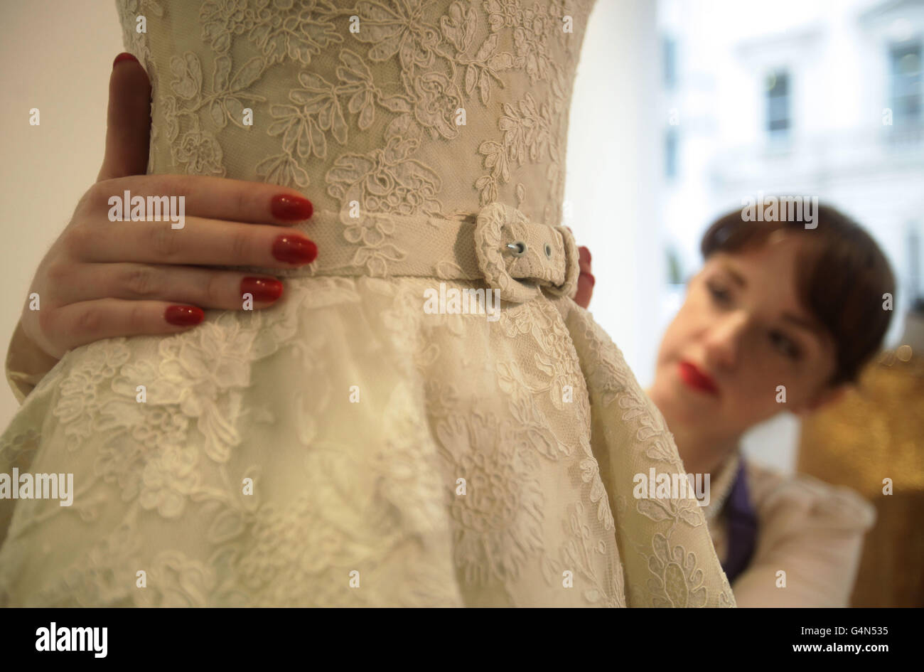 Auction house assistant Lucy Bishop with a dress worn by Audrey Hepburn ...
