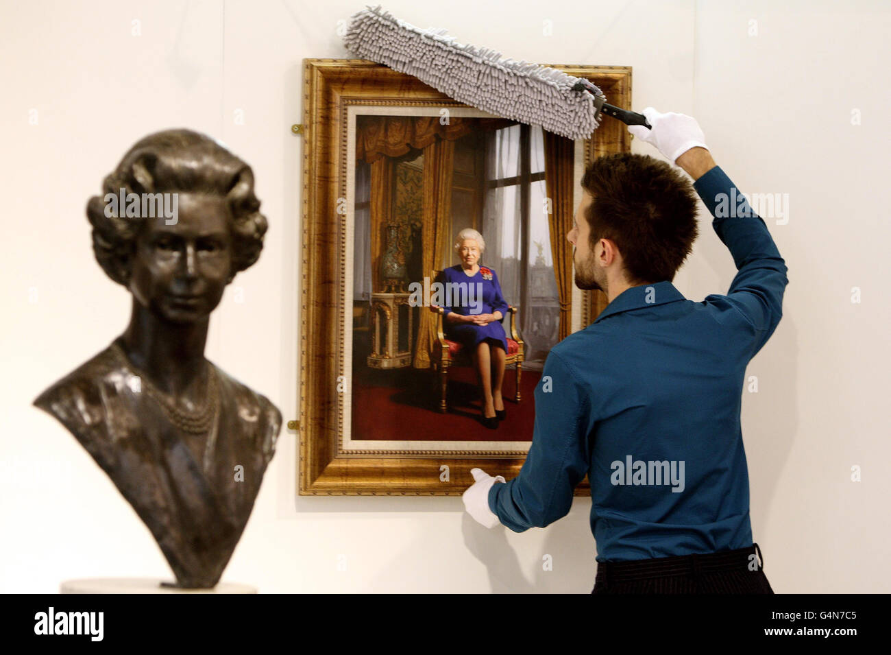 Gallery Manager Alex Prior hangs a portrait of HM Queen Elizabeth II ...