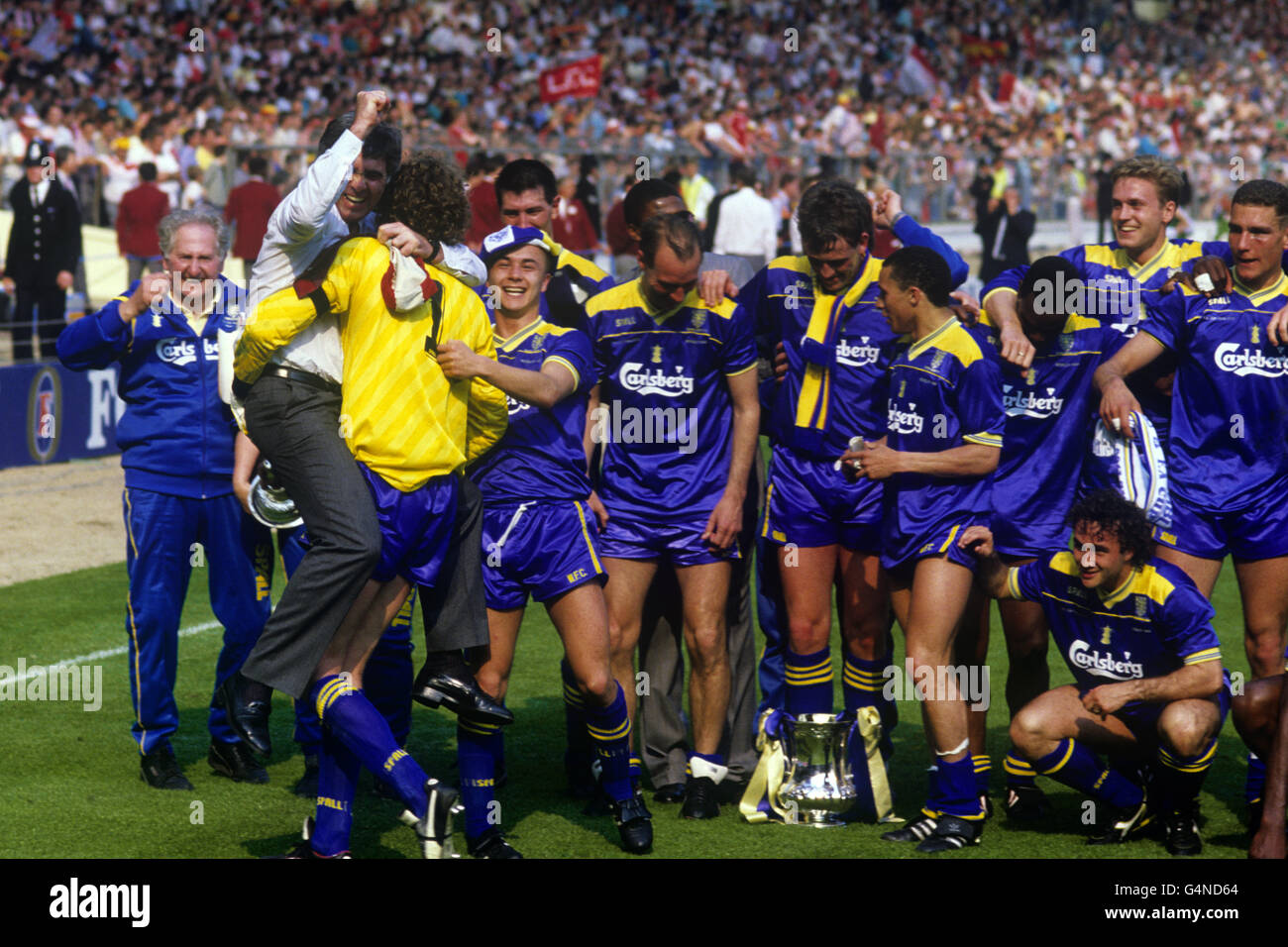 Wimbledon goalkeeper Dave Beasant picks up Manager Bobby Gould as they ...