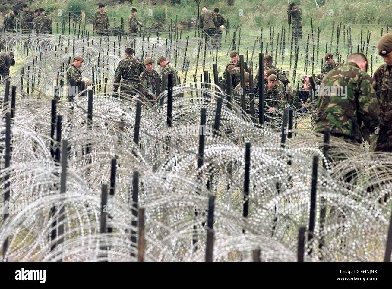British soldiers put up razor wire barriers in the fields around ...