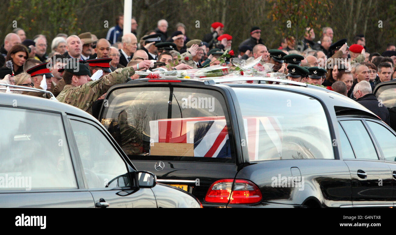 Flowers are placed on hearses carrying the coffins of four soldiers as ...