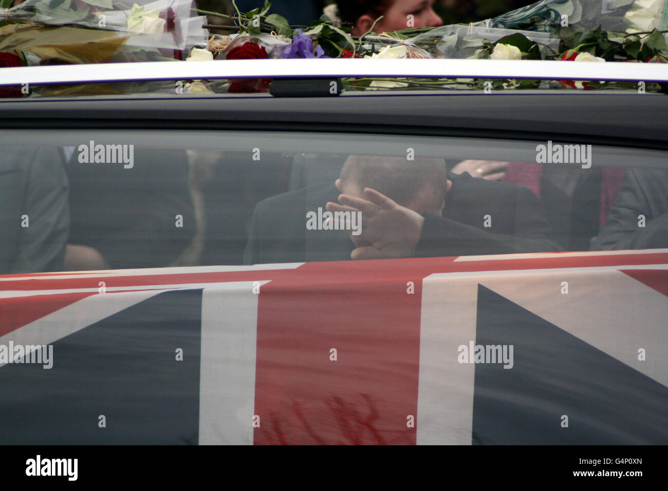 A family member places his hand on the glass of the hearse containing ...