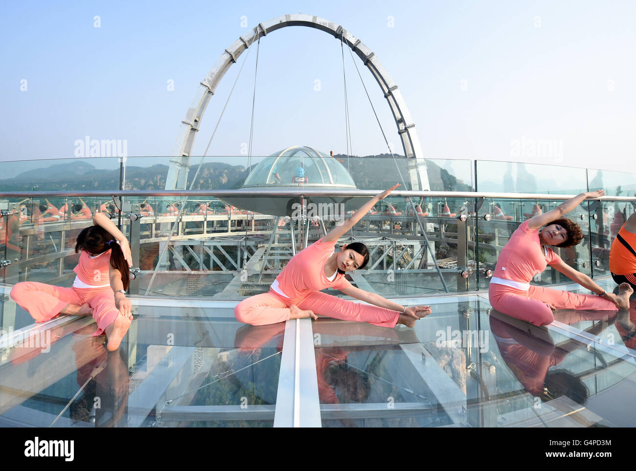 Beijing, China. 20th June, 2016. Yoga lovers practise yoga at a glass ...