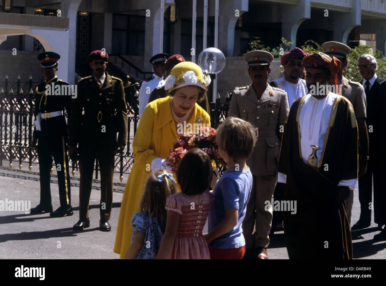 Queen Elizabeth II speaks to children during her walkabout in Muscat ...