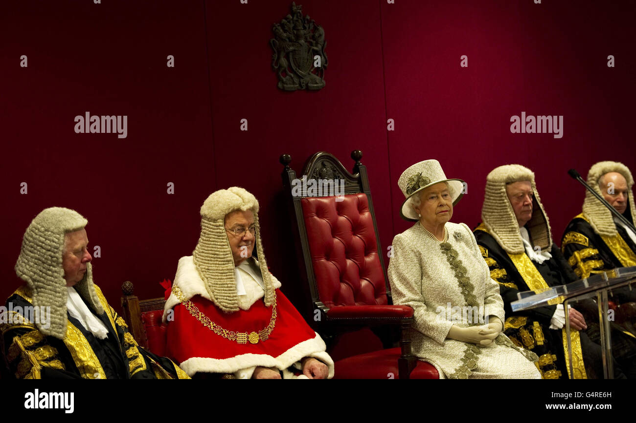 Queen Elizabeth II sits listening to a High Court judge giving a speech ...