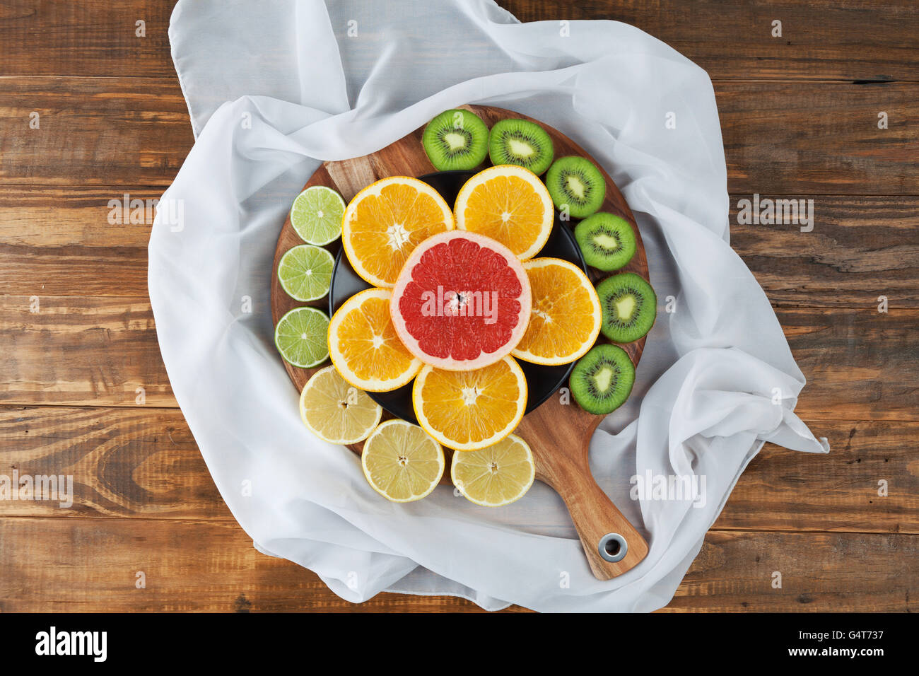 Slices of citrus fruits arranged on round chopping board with elegant ...