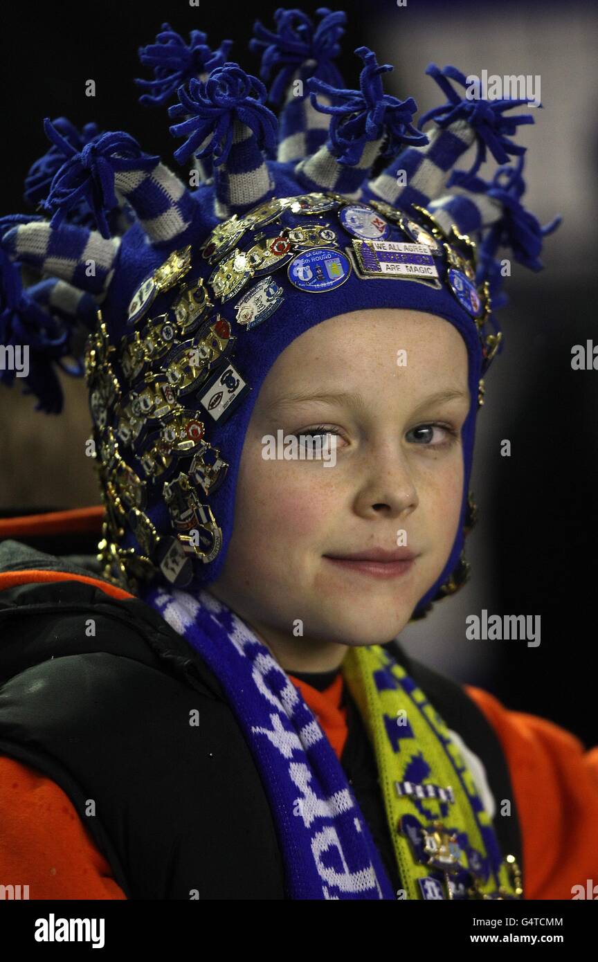A young Everton supporter wears a badge covered hat in the stands Stock ...