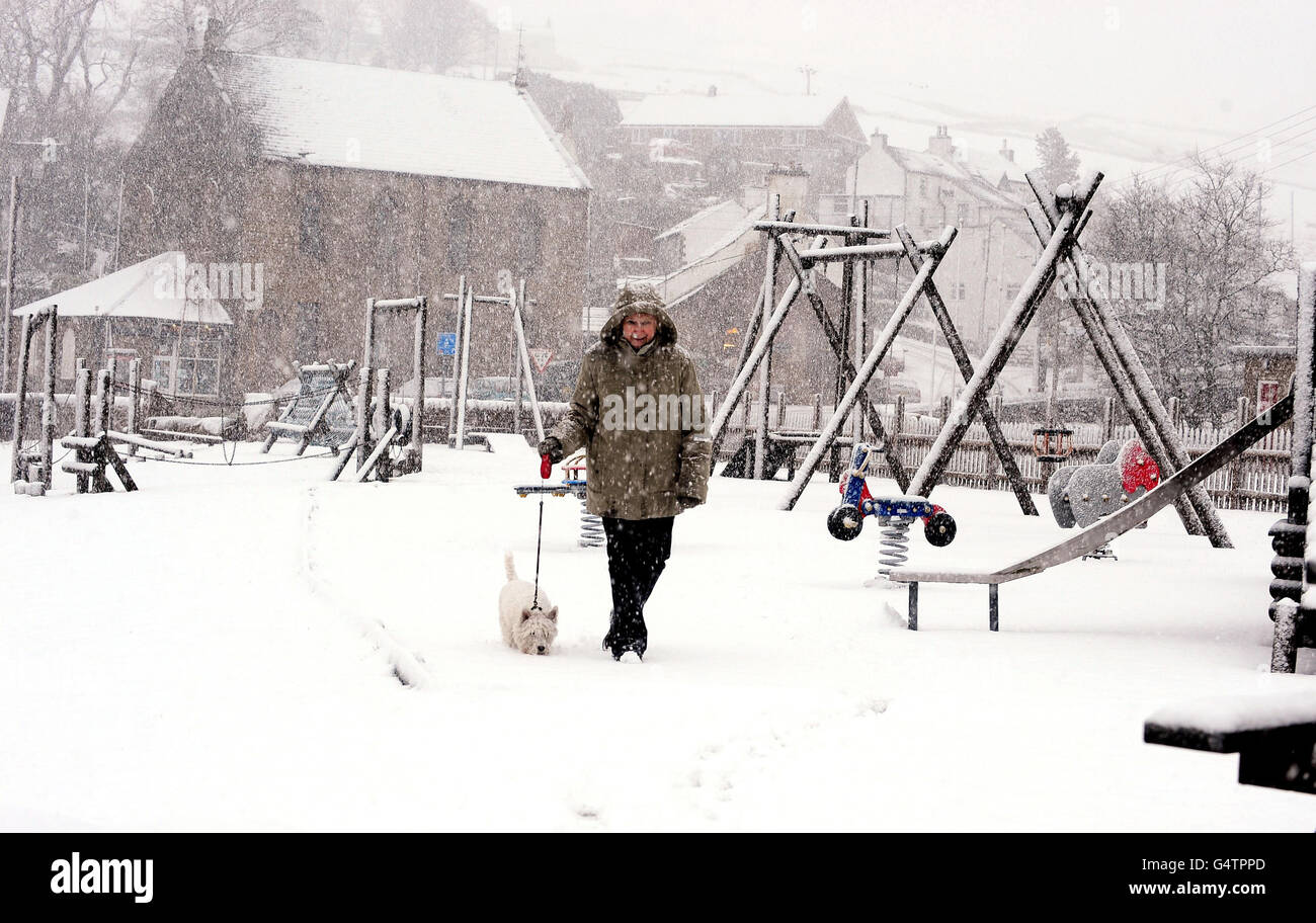 A woman walks her dog in the snow at Nenthead, Cumbria, as the country ...