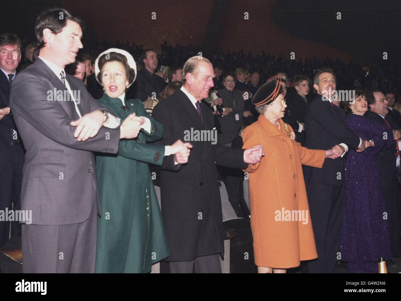 Britain's Queen Elizabeth II (centre) joins hands with those around her ...