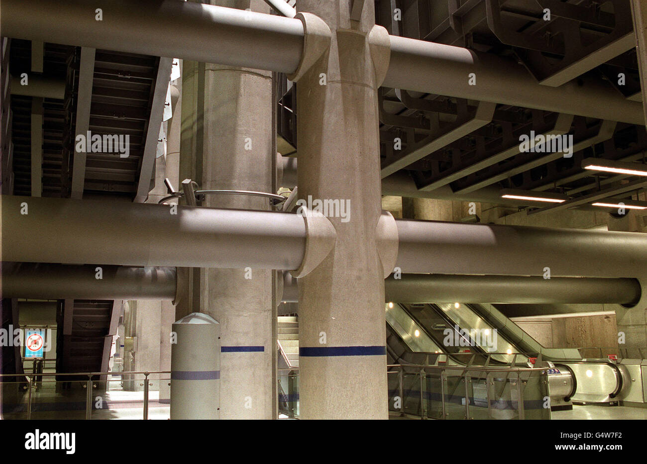 Detail of pipes and a pillar at the bottom of a set of escalators and a ...