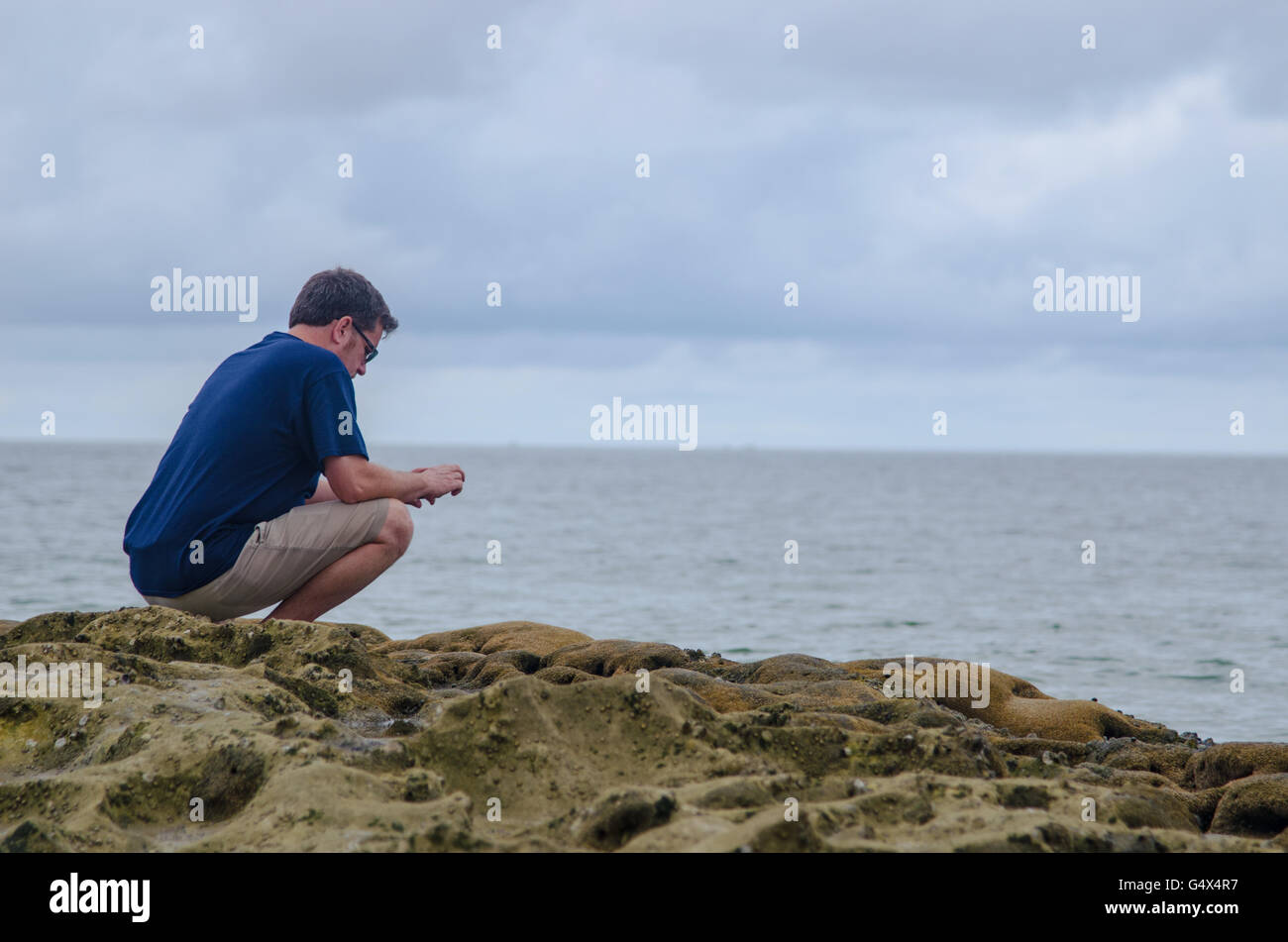 Horizontal image of sitting man photographing on beach against cloudy ...