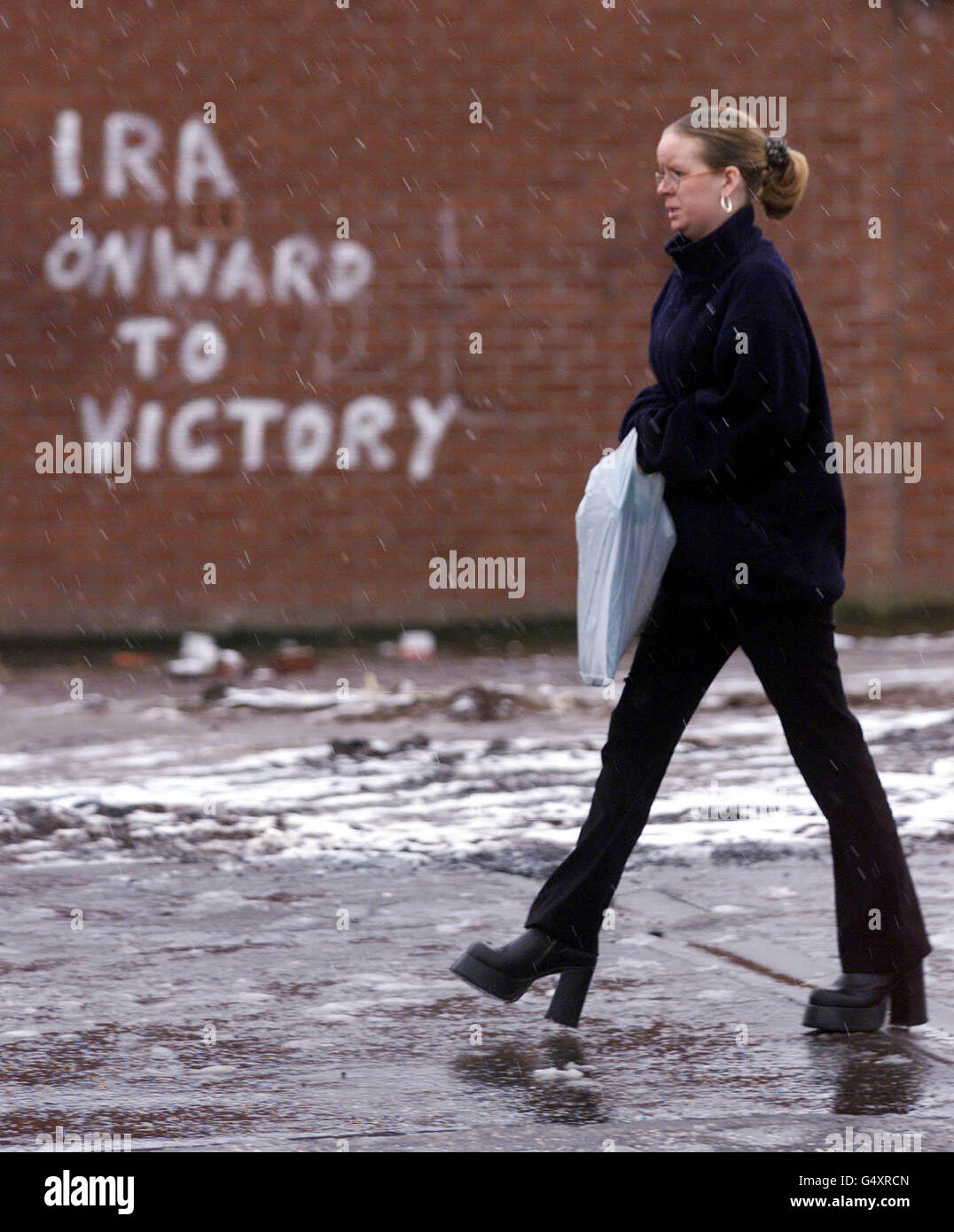 A woman walks past IRA Graffiti in west Belfast. Britain's Prime ...