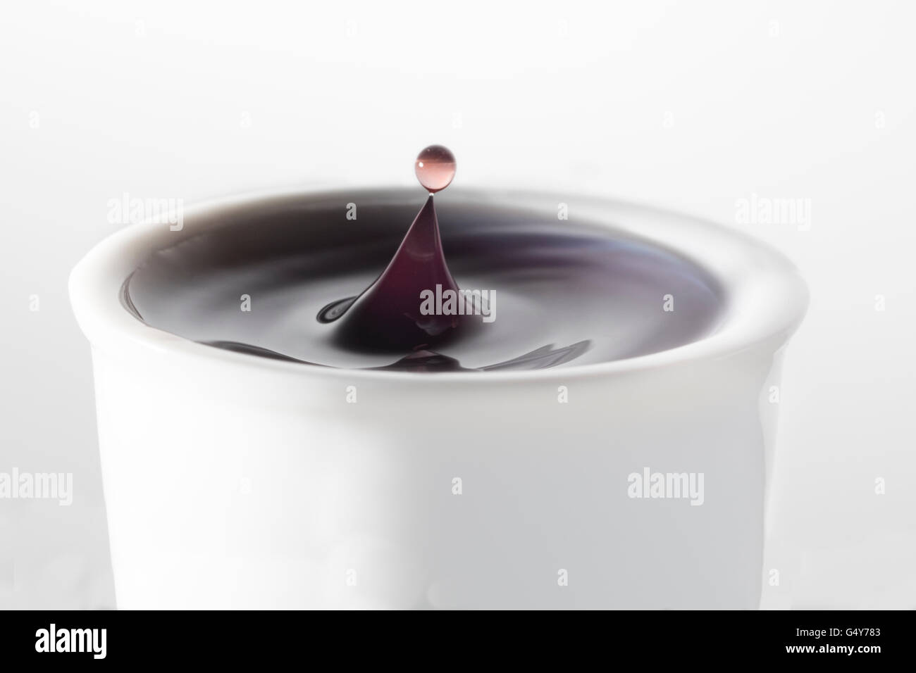 Colored water drop in white cup against white background Stock Photo ...