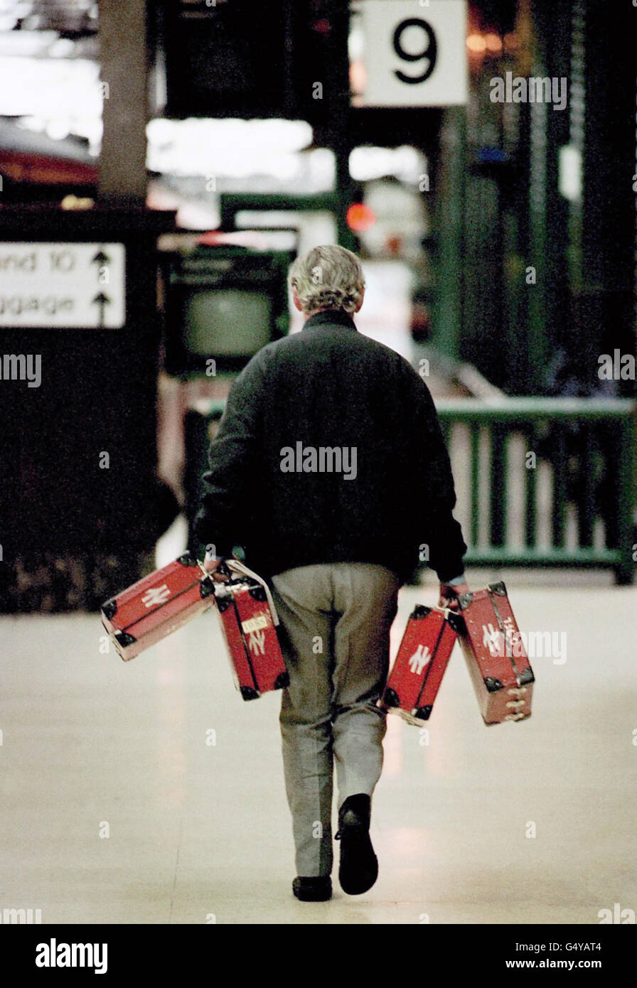 A train guard carries ticket machine boxes along the platform at ...