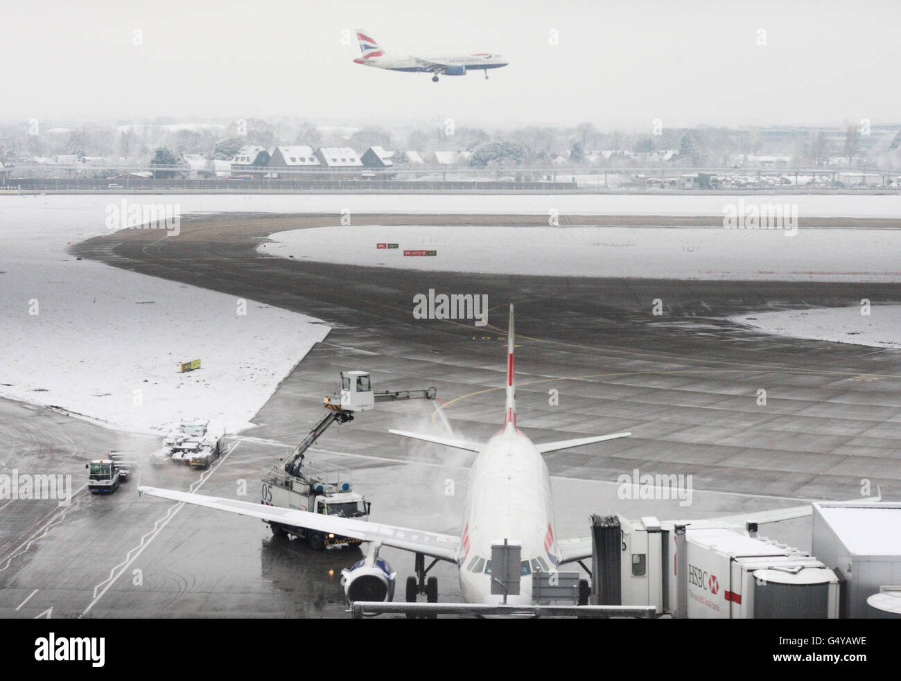 A British Airways plane is de-iced and cleared of snow at Terminal 5 of ...