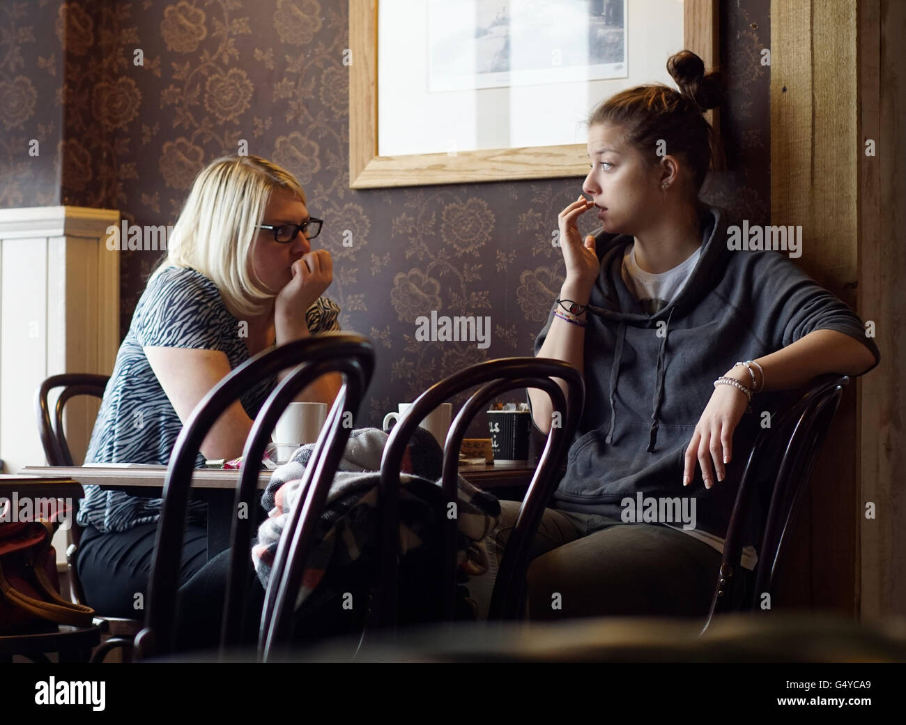 two young women in conversation in cafe Stock Photo - Alamy